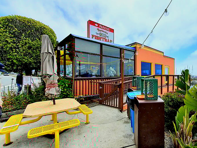The colorful exterior of Barbara's Fishtrap stands like a cheerful sentinel by the sea, its bright orange and blue fa&ccedil;ade promising seafood treasures within.