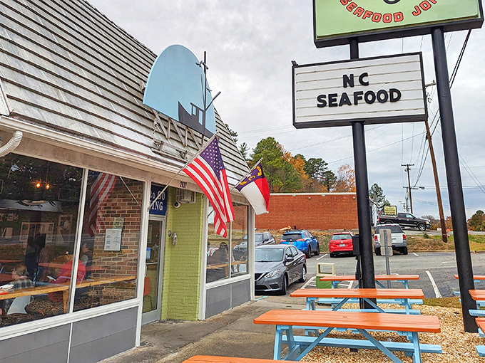 The humble exterior of Saltbox Seafood Joint belies the culinary treasures within. That "NC SEAFOOD" sign is basically a bat signal for hungry North Carolinians.