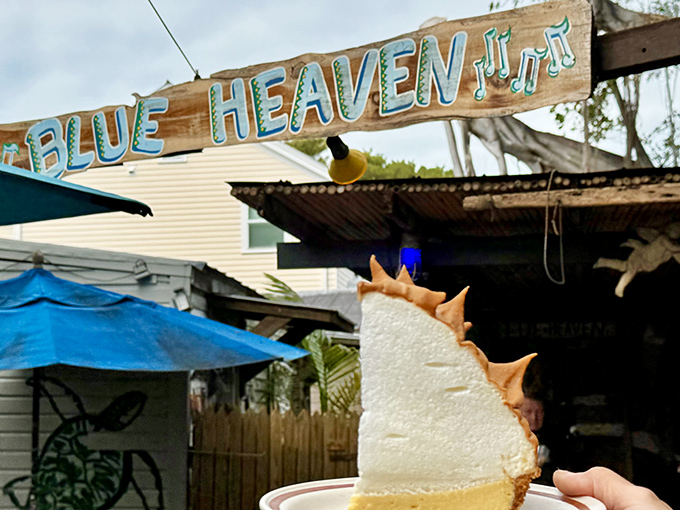 The entrance to Blue Heaven feels like stepping into a tropical fairytale, complete with weathered blue fence, lush foliage, and that signature Key West charm.