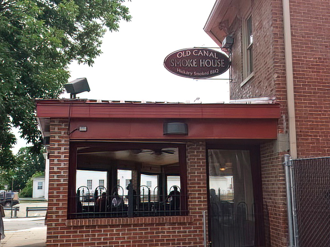 The brick exterior of Old Canal Smoke House welcomes hungry travelers with its warm glow and rustic charm, promising smoky delights within.