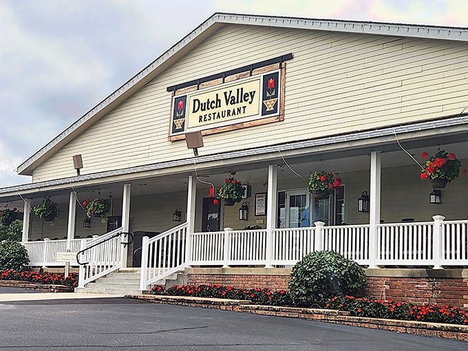 The white clapboard facade of Dutch Valley Restaurant welcomes hungry travelers like a warm hug, complete with inviting porch and hanging flower baskets.