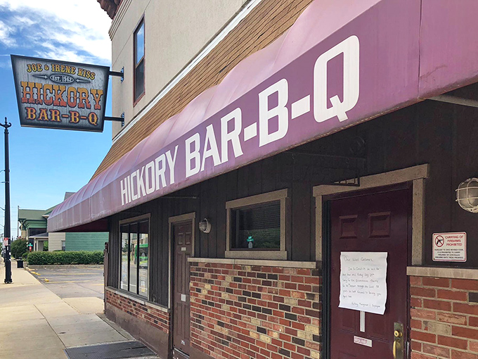 The historic facade of Hickory Bar-B-Q stands like a time capsule on Dayton's streets, its burgundy awning beckoning hungry travelers like a smoky siren call.