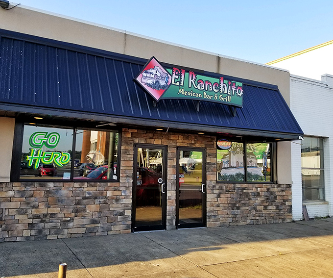 The vibrant storefront of El Ranchito glows like a beacon of culinary promise, its colorful signage and stone facade practically shouting "authentic Mexican food happens here!"