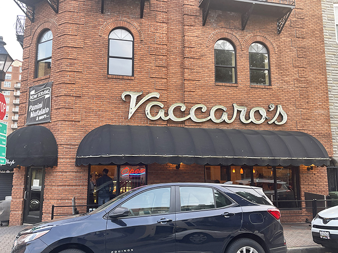 The corner brick building stands like a sentry guarding Little Italy's sweetest treasures, its black awnings a beacon for dessert pilgrims.