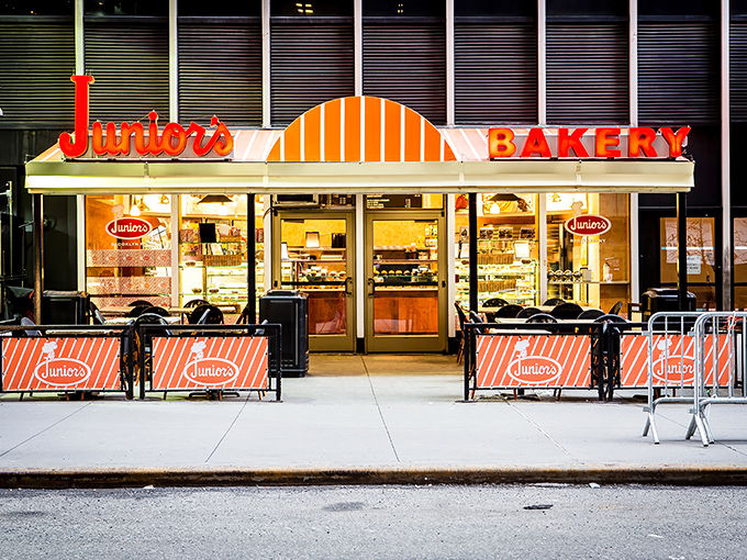 The iconic orange and white fa&ccedil;ade of Junior's glows like a beacon for cheesecake pilgrims, promising sweet salvation in a busy city.