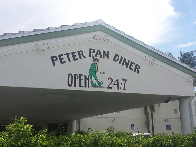 The iconic green sign beckons like a culinary lighthouse amid Florida palms. Peter Pan Diner's exterior promises comfort food magic from 6am to midnight.
