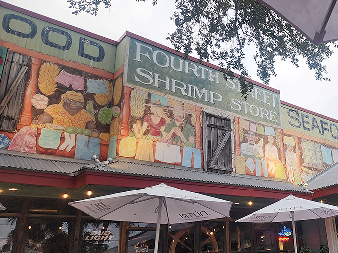 The colorful exterior of Fourth Street Shrimp Store beckons like a siren song, with vibrant murals and red picnic tables promising seafood paradise ahead.