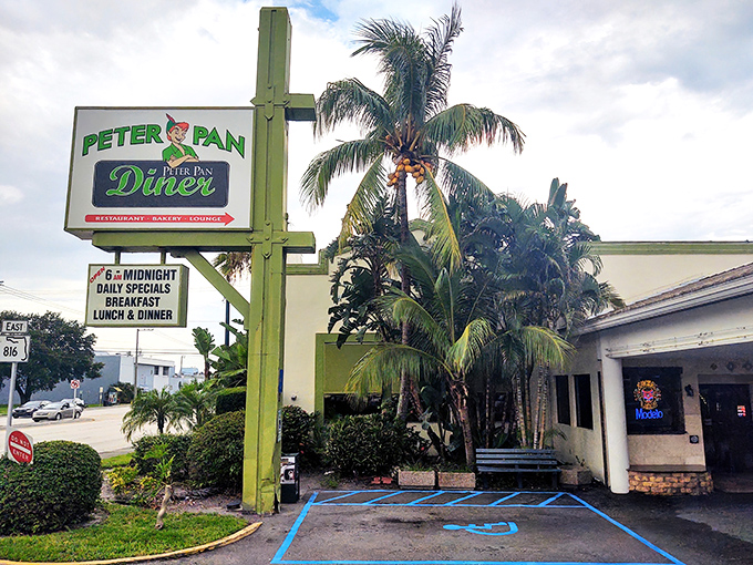 The iconic green sign beckons like a culinary lighthouse amid Florida palms. Peter Pan Diner's exterior promises comfort food magic from 6am to midnight.