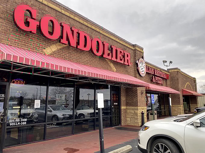 The bold red Gondolier sign beckons like a lighthouse for pasta pilgrims, promising Italian comfort under those distinctive striped awnings.
