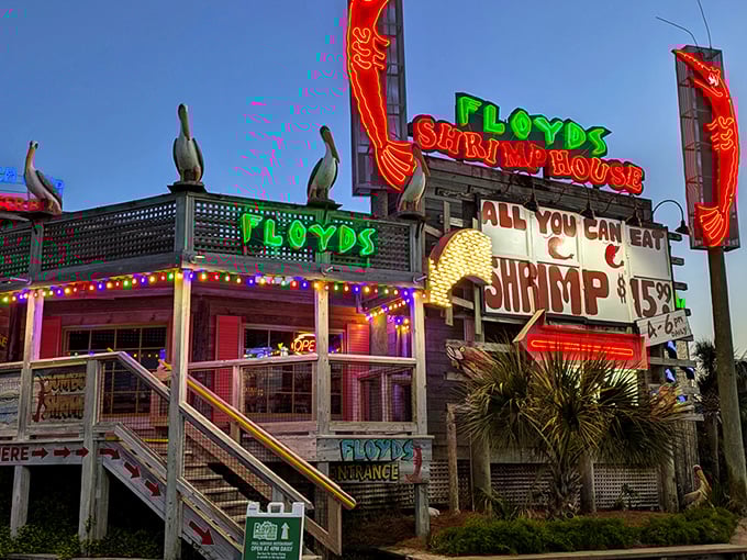 Floyd's neon sign blazes against the twilight sky like a lighthouse for hungry sailors, complete with pelican sentinels standing guard over shrimp paradise.