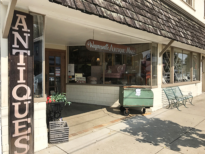 The storefront beckons with vintage charm, that iconic vertical "ANTIQUES" sign practically whispering, "Come in, your grandmother's favorite lamp is waiting for you."