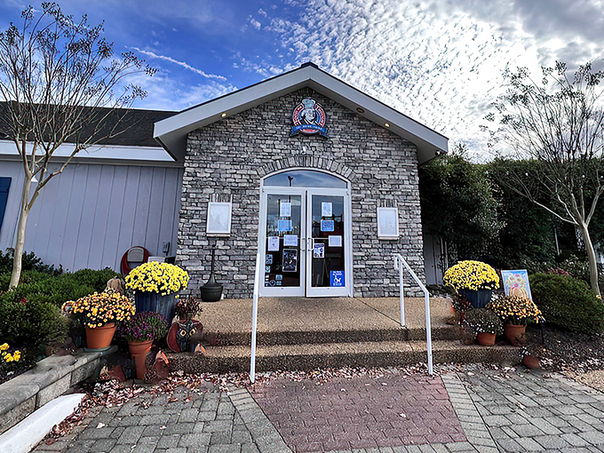 A charming stone entrance invites you to enjoy a meal surrounded by vibrant fall flowers and a welcoming, cozy atmosphere.