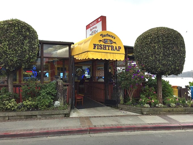 The colorful exterior of Barbara's Fishtrap stands like a cheerful sentinel by the sea, its bright orange and blue fa&ccedil;ade promising seafood treasures within.
