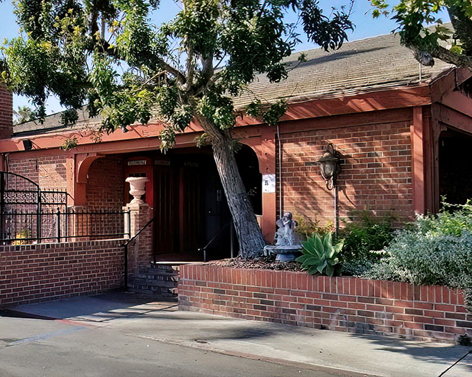 The iconic red sign beckons like a lighthouse for meat lovers. Palm trees and brick exterior create that perfect California-meets-Old-England vibe.
