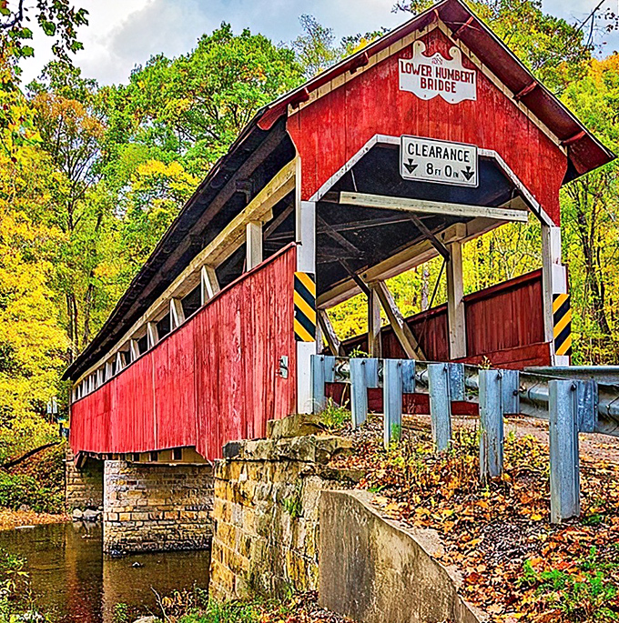The Lower Humbert Bridge stands like a crimson sentinel against autumn's golden backdrop, a perfect postcard from Pennsylvania's storied past.