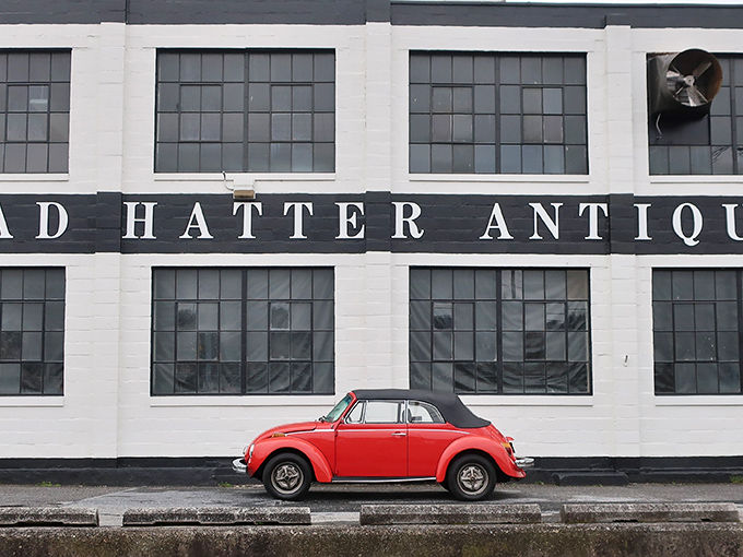 The white facade of Mad Hatter Antiques stands like a portal to the past, with blue "OPEN" flags beckoning treasure hunters to step inside and explore.