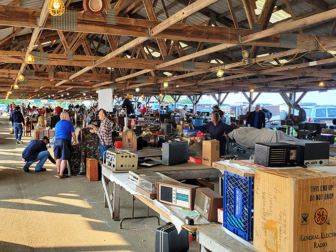 Treasure hunters navigate the cavernous barn-like structure where decades of history await discovery beneath rustic wooden beams and warm lighting.