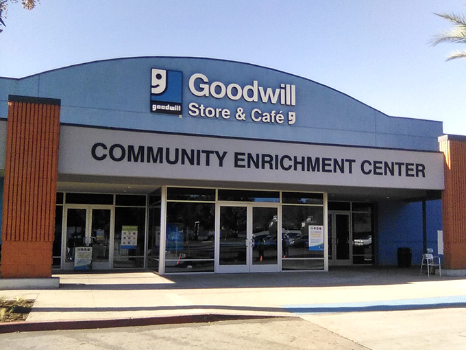 The blue-fronted Goodwill Southern California Community Enrichment Center stands ready to welcome bargain hunters beneath swaying palm trees, a treasure cave disguised as a retail store.