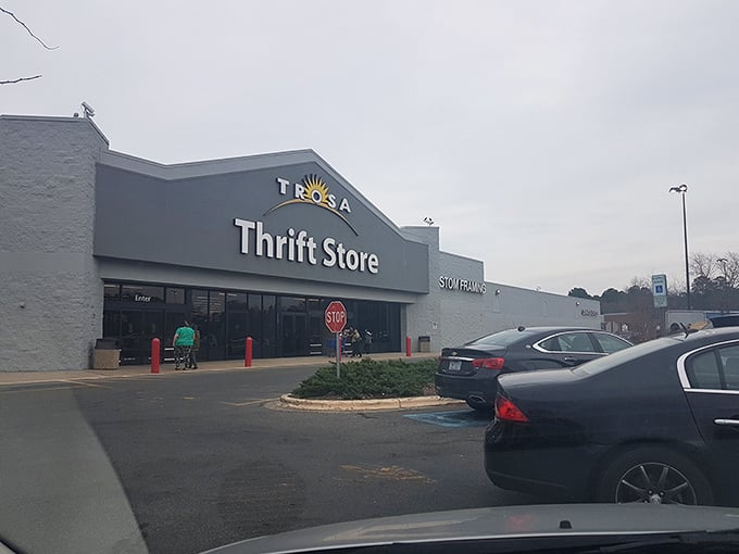 The TROSA Thrift Store stands proudly against a blue sky, its cheerful sun logo promising treasures within that are as bright as the day outside.