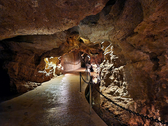 The illuminated pathway through Linville Caverns beckons visitors into a subterranean world where time is measured in millennia, not minutes.