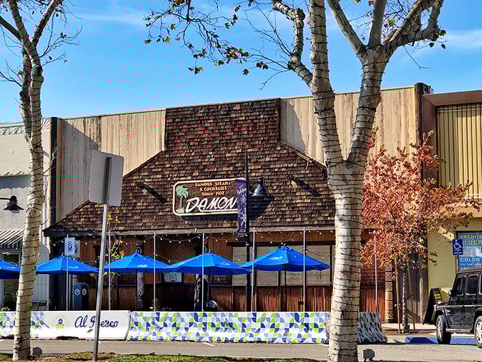 Damon's Steak House sits like a neighborhood treasure, promising carnivorous adventures behind those welcoming blue umbrellas.