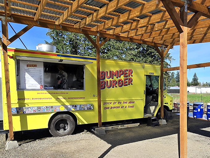 The bright yellow Bumper Burger food truck stands like a culinary lighthouse, beckoning hungry travelers under its rustic wooden shelter. Simple setting, extraordinary flavors.