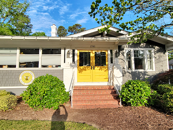 The charming cottage exterior with its signature yellow door promises culinary magic within. Like finding a secret garden that happens to serve incredible biscuits.