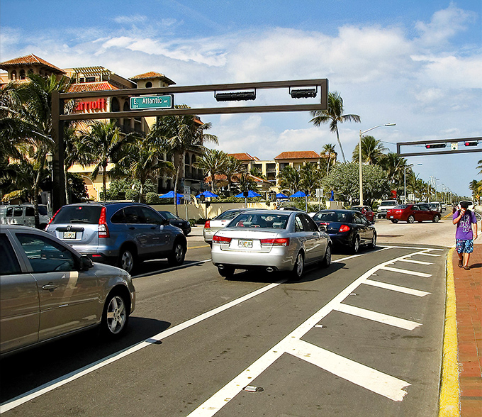 Atlantic Avenue's bustling intersection where paradise meets practicality. The traffic light gives you time to appreciate palm trees instead of snow shovels.