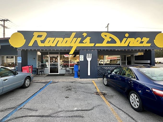 The iconic navy blue exterior with bright yellow lettering announces Randy's Diner like a beacon for breakfast lovers. That giant fork on the wall? It's pointing you toward hash brown nirvana. 