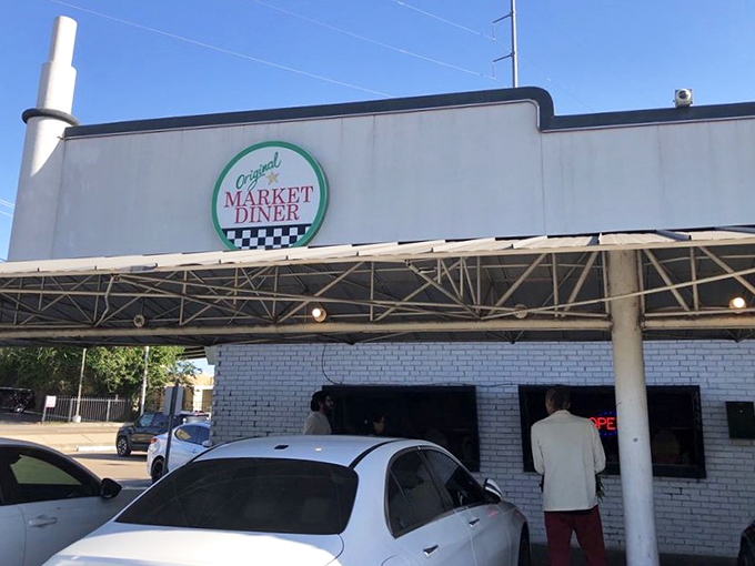 The iconic green and white signage promises comfort food salvation, standing defiantly against Dallas's modernizing skyline.