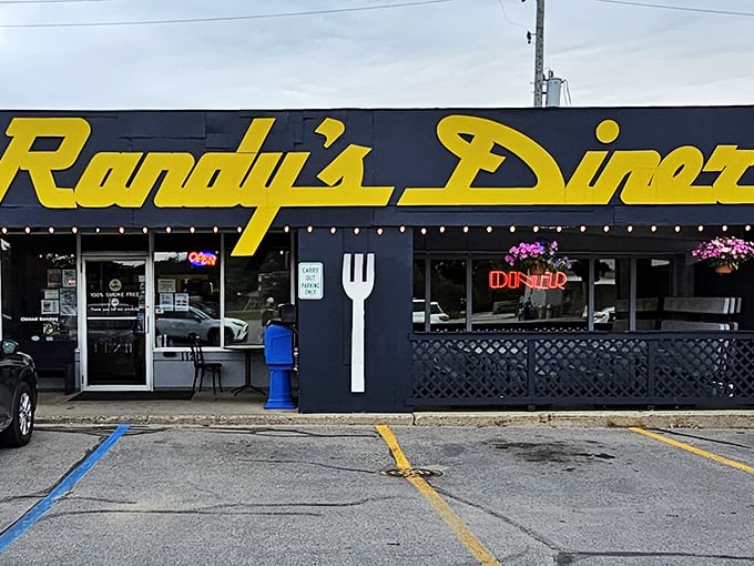 The iconic navy blue exterior with bright yellow lettering announces Randy's Diner like a beacon for breakfast lovers. That giant fork on the wall? It's pointing you toward hash brown nirvana. 