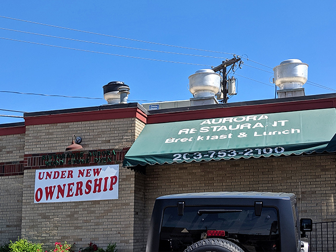 The classic roadside charm of Aurora Diner beckons hungry travelers with its promise of comfort food and that unmistakable blue-umbrella welcome.