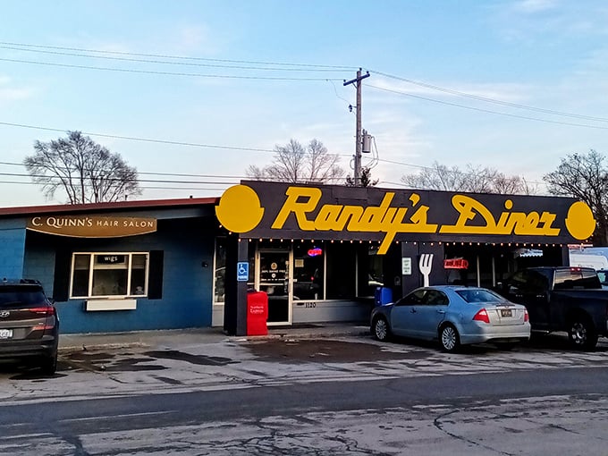 The iconic navy blue exterior with bright yellow lettering announces Randy's Diner like a beacon for breakfast lovers. That giant fork on the wall? It's pointing you toward hash brown nirvana. 