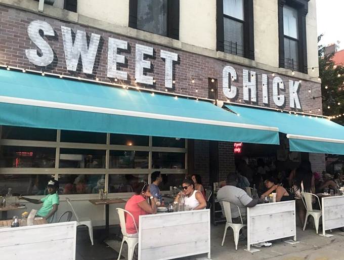 The unmistakable pink brick exterior of Sweet Chick beckons hungry passersby with its warm glow and picnic tables that practically whisper, "Pull up a seat, friend."