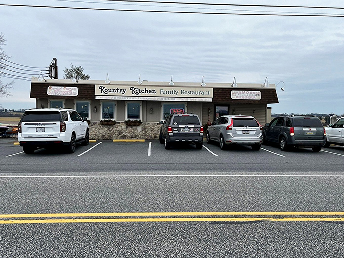 The unassuming exterior of Kountry Kitchen Family Restaurant, where hanging flower baskets and stone foundation hint at the homey comfort waiting inside.