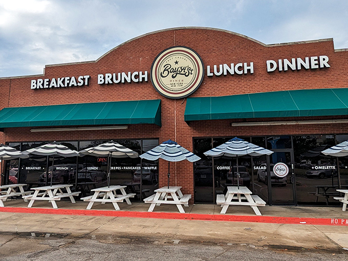 The brick facade with teal awnings isn't just inviting&mdash;it's practically shouting "Come get breakfast!" Those white picnic tables are waiting for your morning revelation.