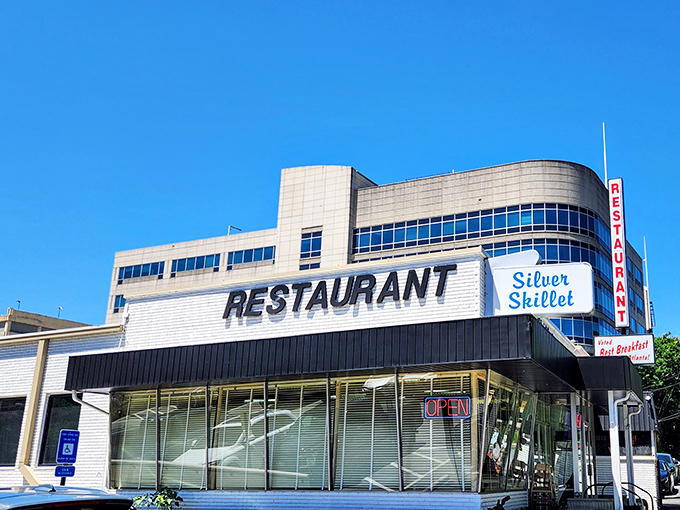 The Silver Skillet stands proudly against Atlanta's blue sky, its vintage sign a beacon for hungry souls seeking breakfast salvation in the city's bustling landscape.