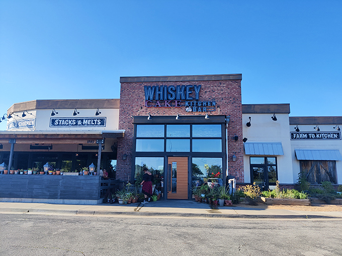 Rustic brick meets modern charm at Whiskey Cake's inviting exterior. The patio planters hint at the farm-to-table philosophy waiting inside.