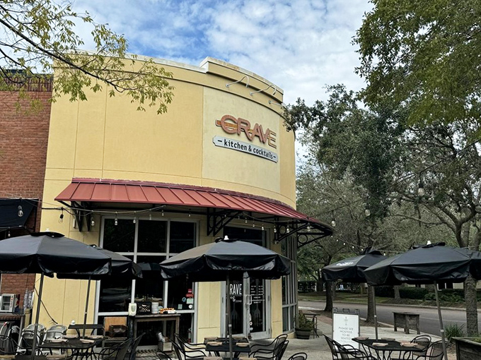 The curved facade of Crave beckons like a cheesy siren call. Those red umbrellas promise refuge from both sun and boring meals.