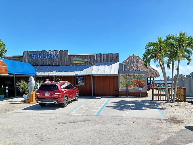 The weathered wooden exterior of The Old Fish House screams "authentic Florida" with its blue signage and that charming manatee statue standing guard at the entrance. 