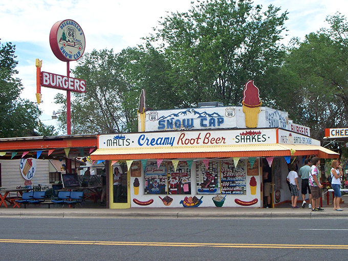 The Snow Cap's technicolor facade stands as a Route 66 landmark, complete with ice cream cone signage and colorful bunting that screams "Americana lives here!"