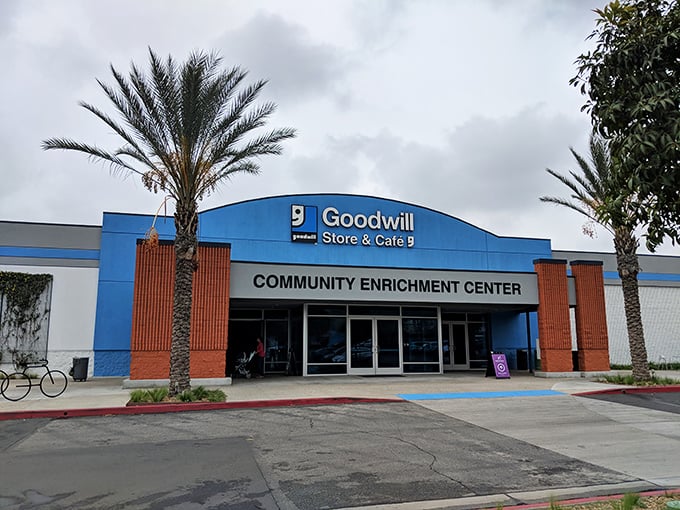 The blue-fronted Goodwill Southern California Community Enrichment Center stands ready to welcome bargain hunters beneath swaying palm trees, a treasure cave disguised as a retail store.