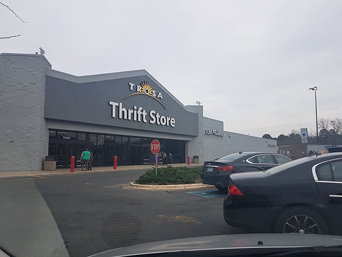 The TROSA Thrift Store stands proudly against a blue sky, its cheerful sun logo promising treasures within that are as bright as the day outside.