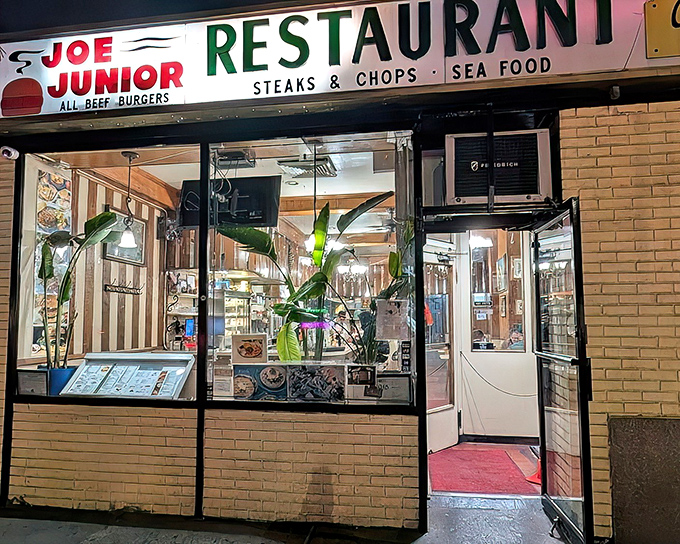 The iconic Joe Jr. sign promises three essential food groups: all-beef burgers, steaks & chops, and seafood. Classic New York diner perfection awaits inside.