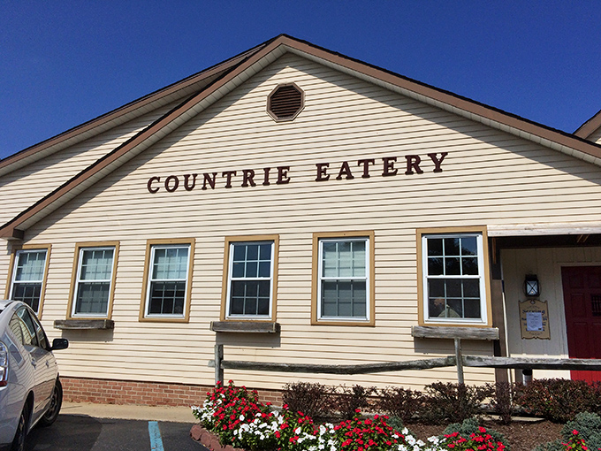 The Countrie Eatery's charming white clapboard exterior with its iconic cow sign promises comfort food paradise before you even step through the door.