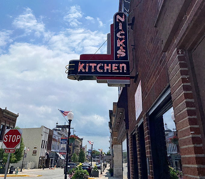 The iconic neon sign of Nick's Kitchen stands as a beacon of comfort food in downtown Huntington, promising delicious memories since 1908.