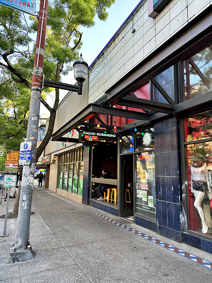 The vibrant triangular sign beckons like a neon North Star for hungry wanderers. Colorful string lights add a festive touch to Broadway's bustling scene.