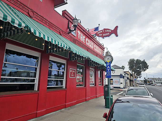 The iconic crimson exterior of The Crab Cooker, with its cheeky "DON'T LOOK UP HERE" fish sign, stands as Newport Beach's delicious rebellion against pretension.