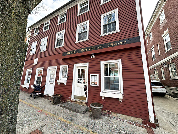 The iconic crimson colonial exterior of Red's Sandwich Shop stands as proudly in Salem as Paul Revere once did, beckoning hungry visitors with historical charm.