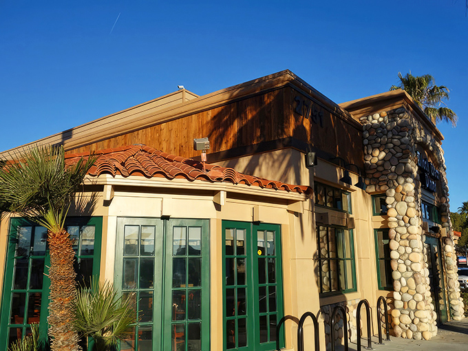 The rustic stone-and-timber facade of Black Bear Diner stands like a mountain lodge mirage in the Nevada desert, promising comfort food salvation to weary travelers.